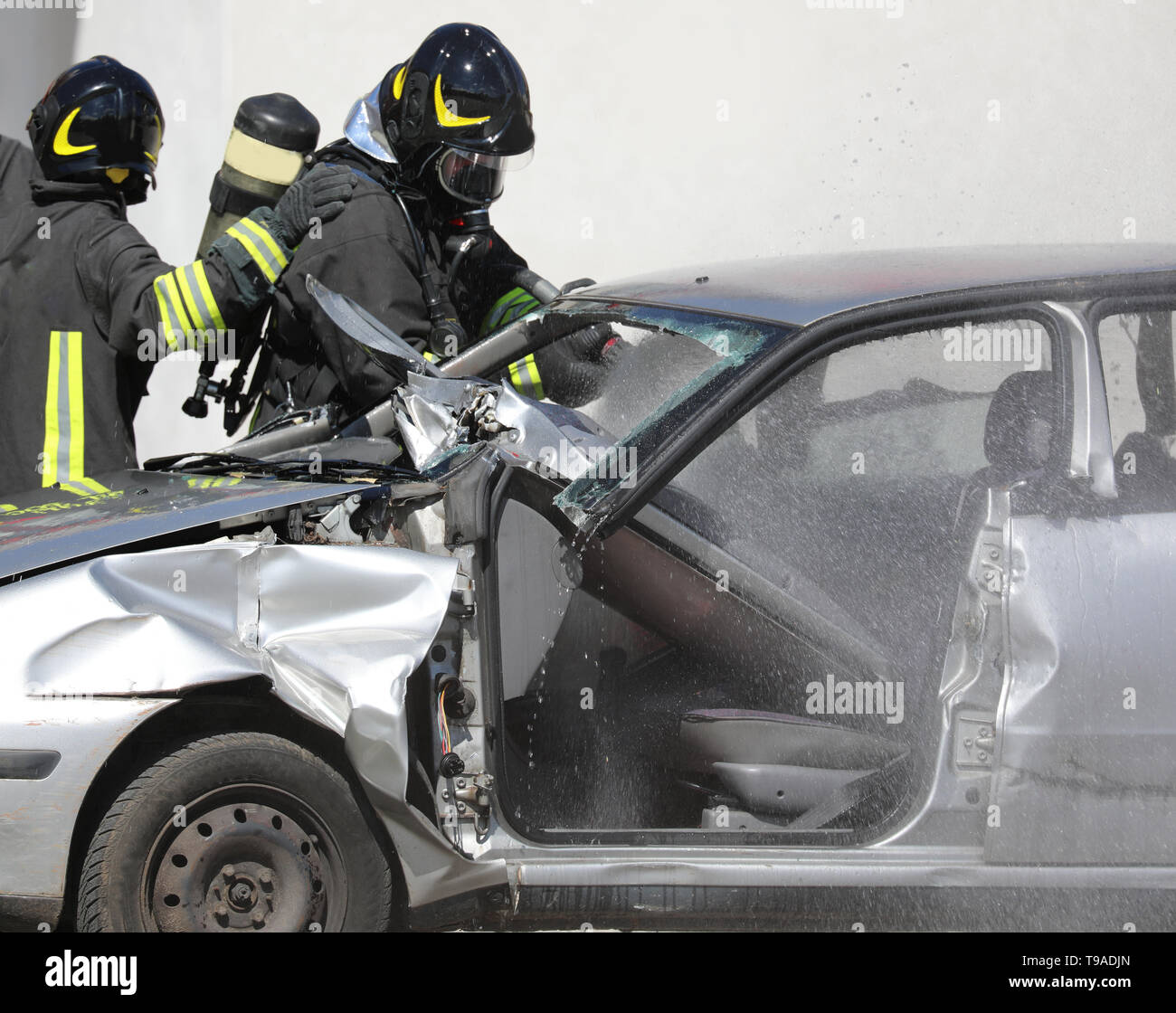 Team of firefighters during fire fighting of a destroyed car after a ...