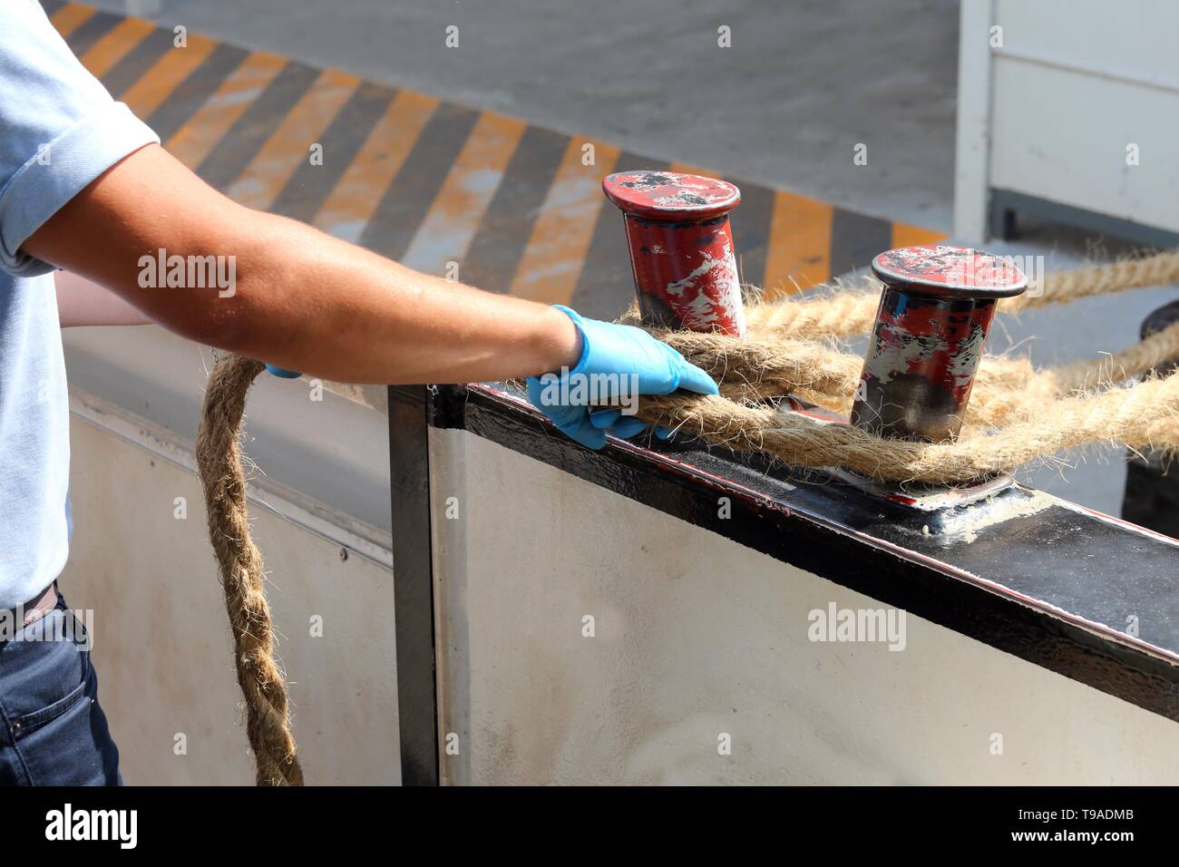 sailor ties a hemp rope to the dock to facilitate the mooring of a boat ...