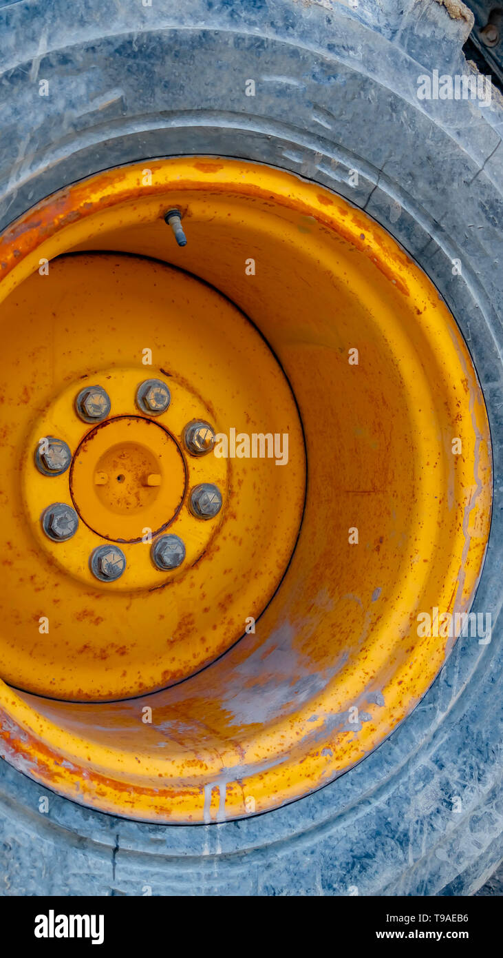Clear Vertical Close up of the wheel of a yellow loader parked on the ...
