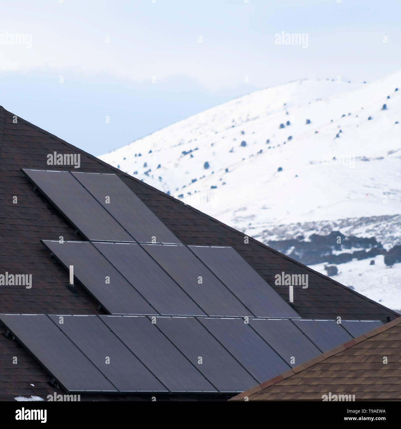 Square Solar panels installed on the dark roof of a home with snow in ...