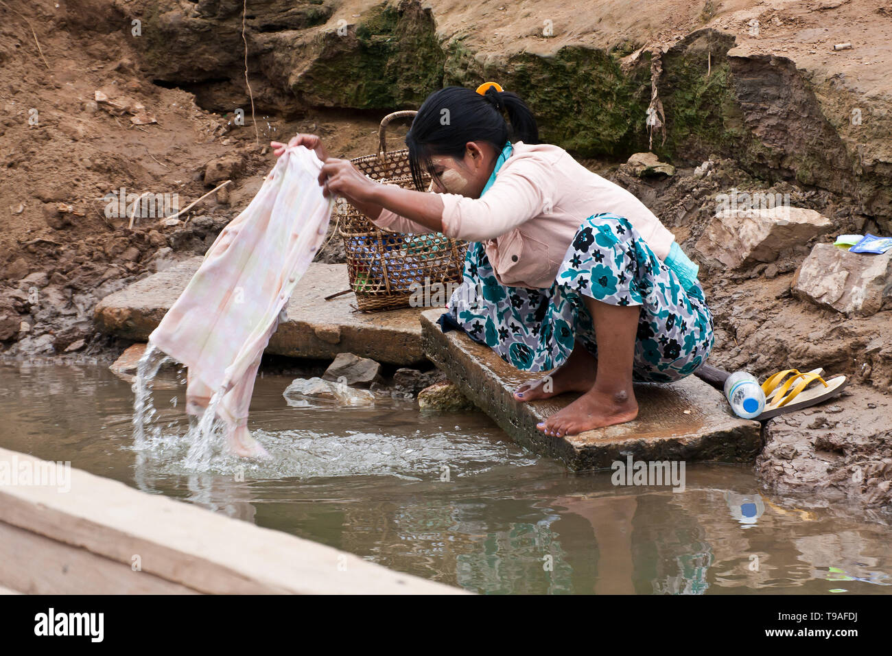 A young Burmese woman is washing clothes in the Irrawaddy River ...
