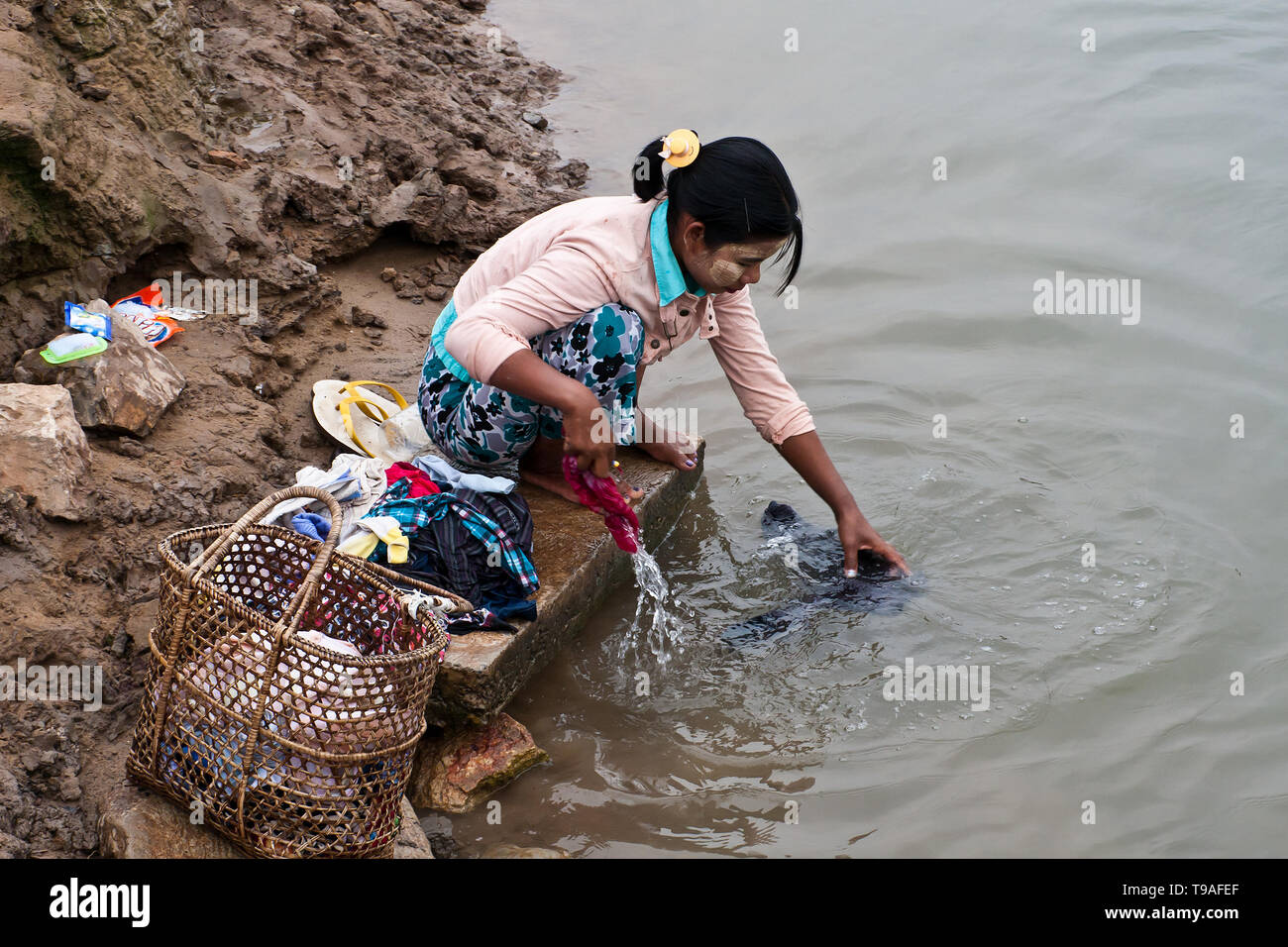 A young Burmese woman is washing clothes in the Irrawaddy River ...