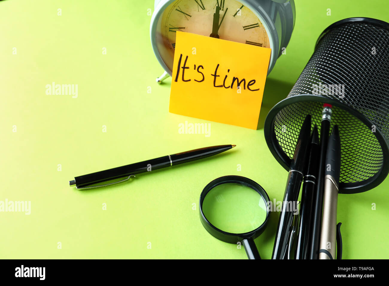 Paper sheet with text IT'S TIME, stationery and alarm clock on color ...