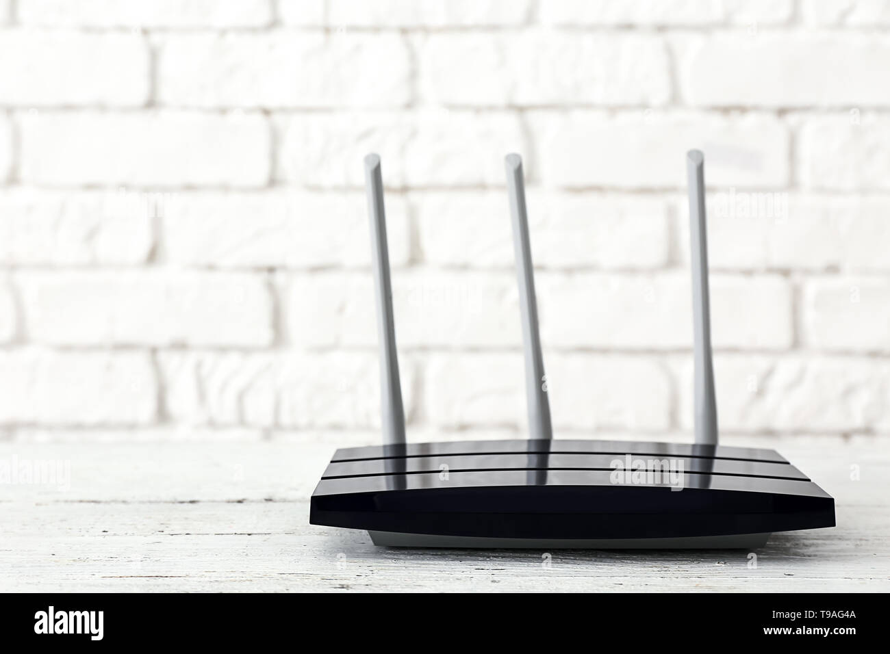 Modern wi-fi router on light table near brick wall Stock Photo - Alamy