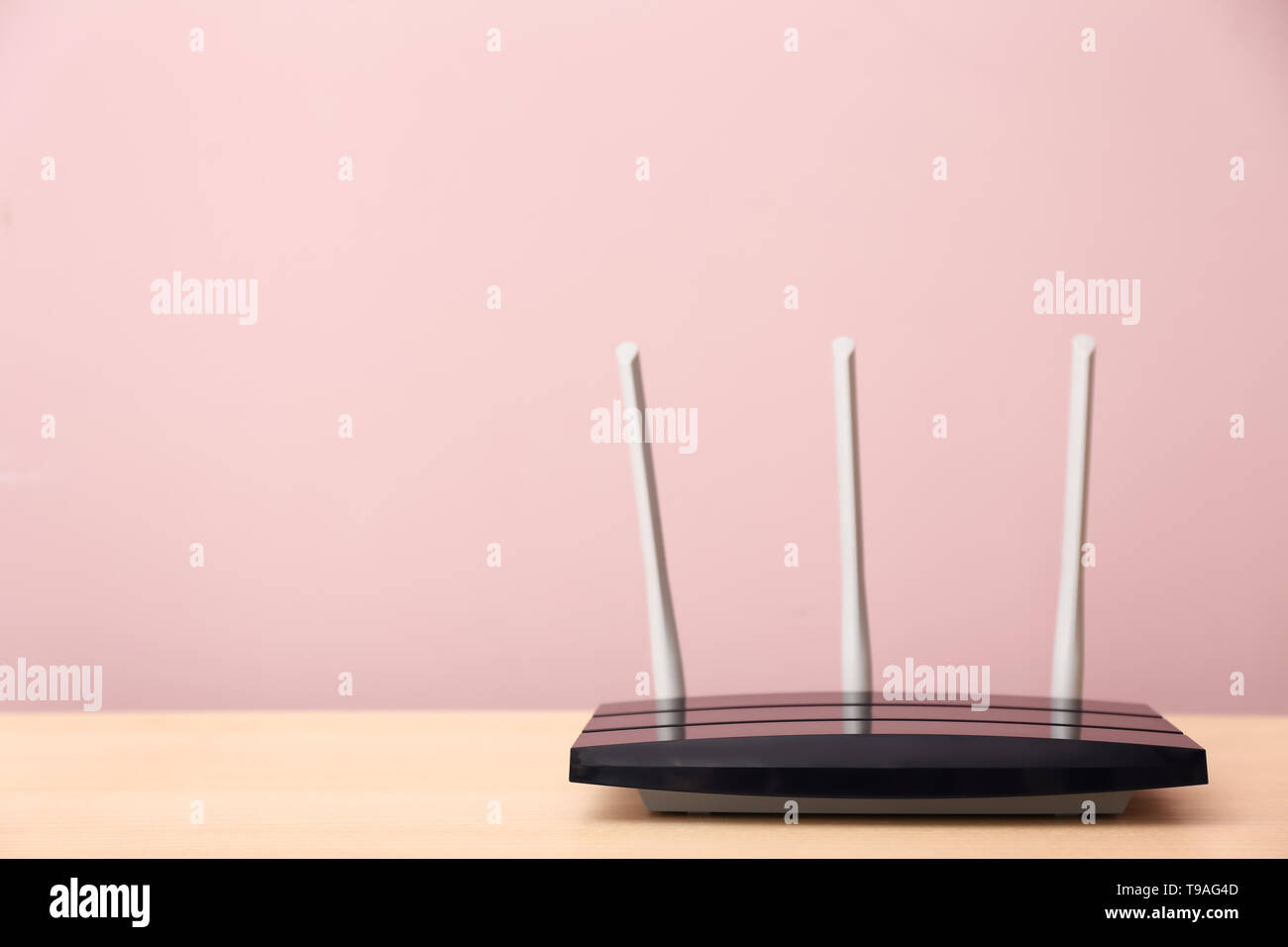 Modern wi-fi router on wooden table against color background Stock ...