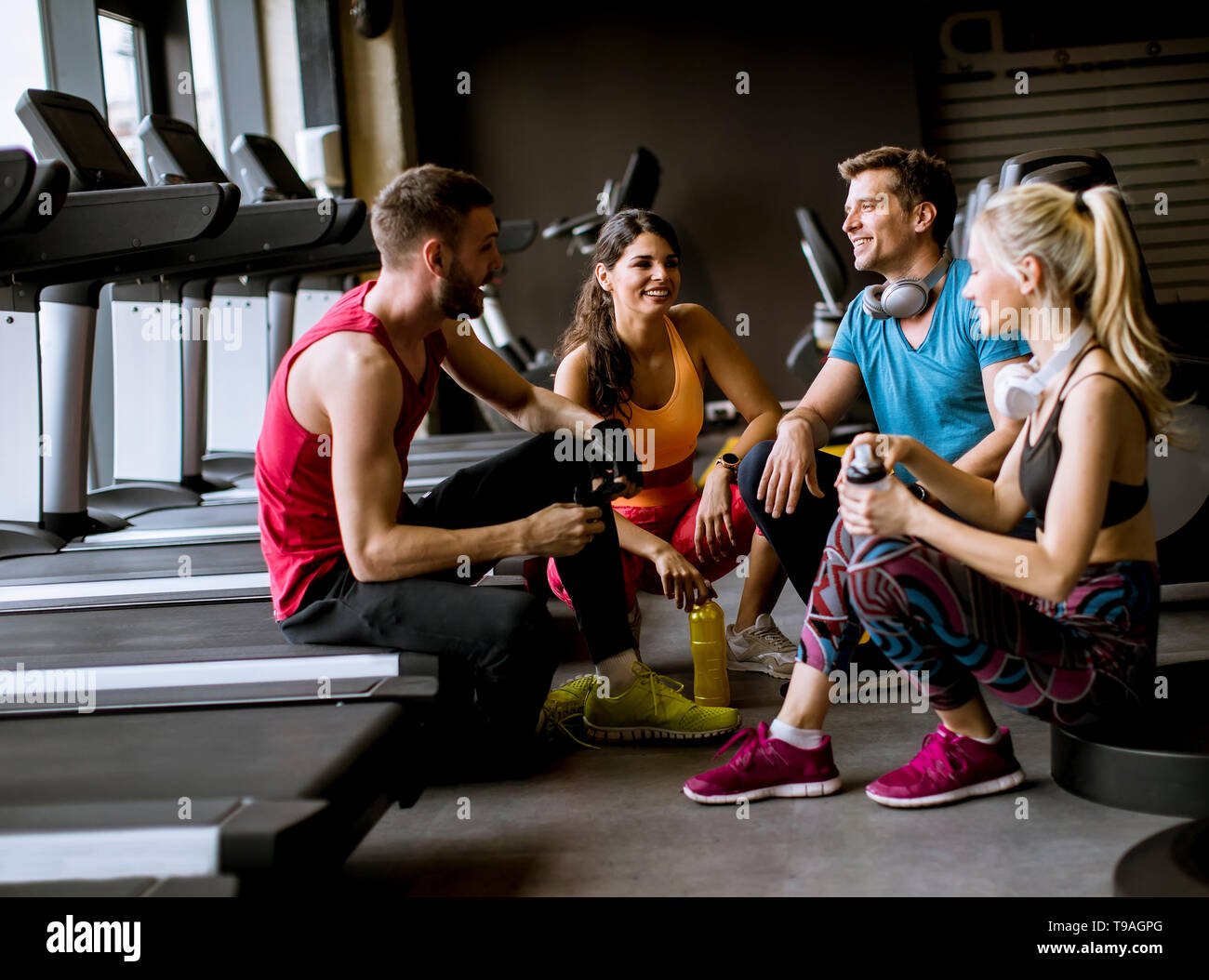 Group of young people in sportswear talking and laughing together while ...