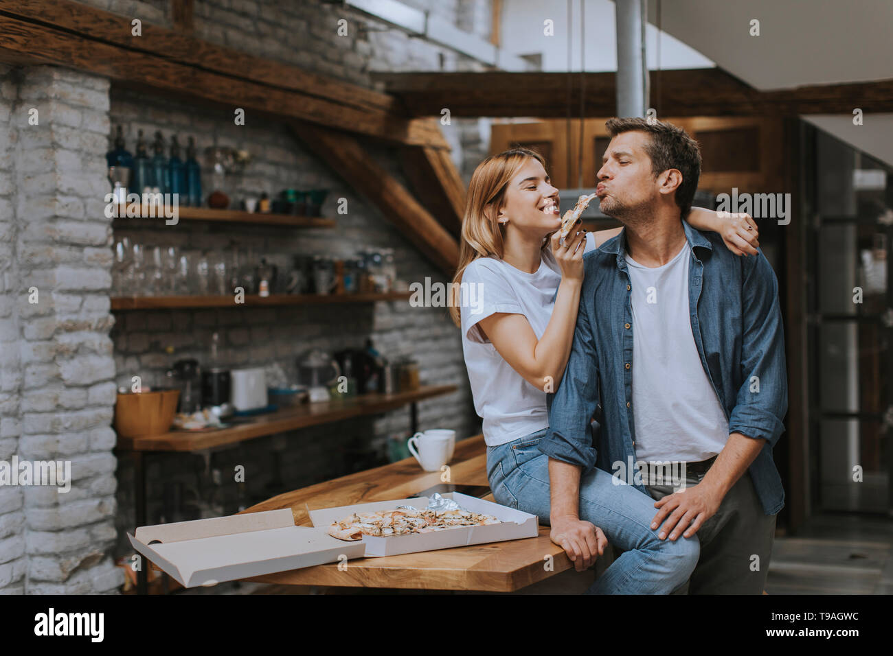 Young couple in love eating pizza for sneck in the rustic home Stock ...