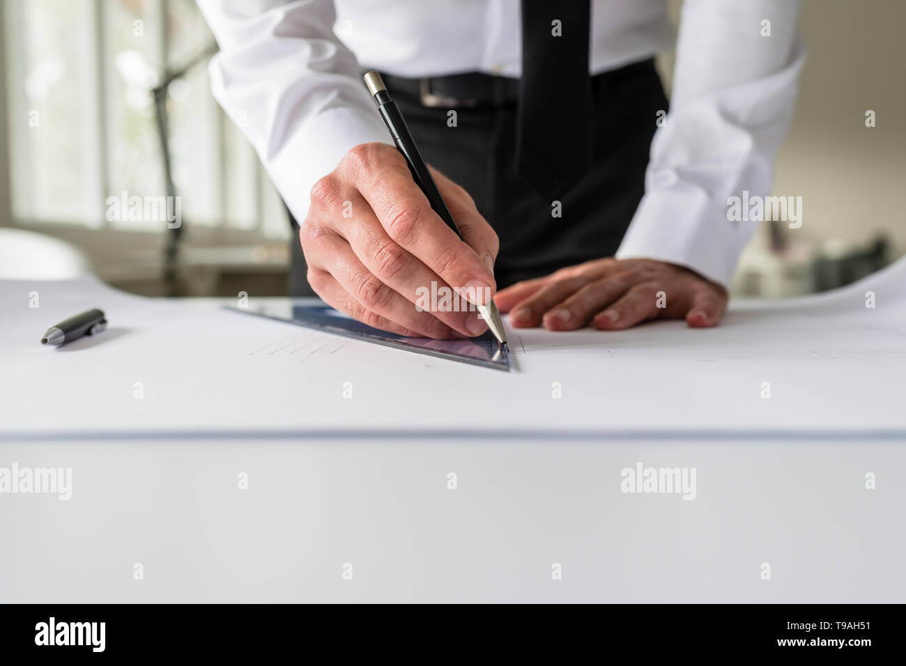 Architect or designer drawing a draft on a paper using a pencil and a ...