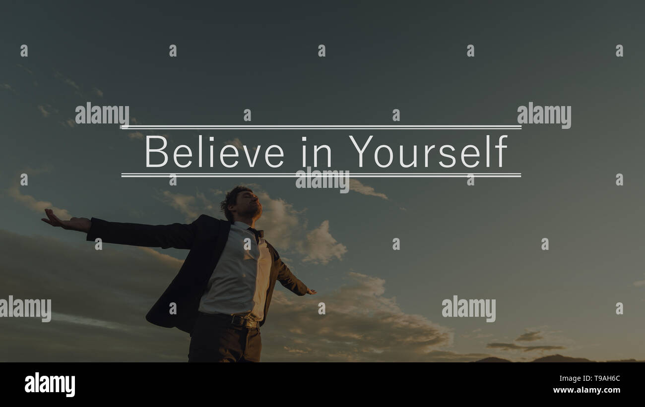 Believe in yourself sign above a young businessman in a suit enjoying ...
