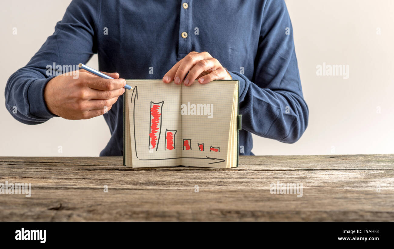 Businessman showing his notebook with falling financial graphs colored in red showing decrease ...