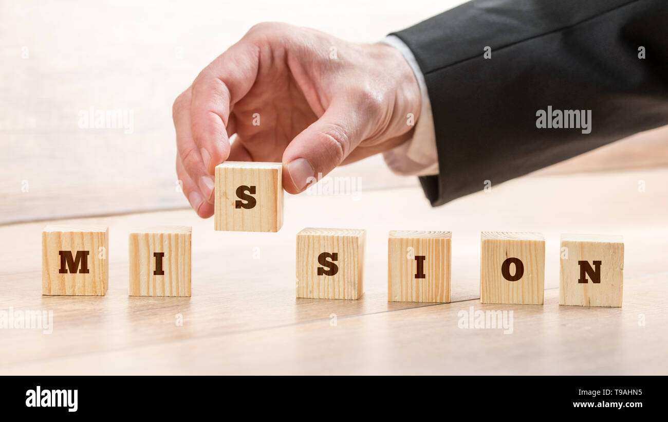 Closeup of businessman creating a word Mission with seven wooden cubes ...