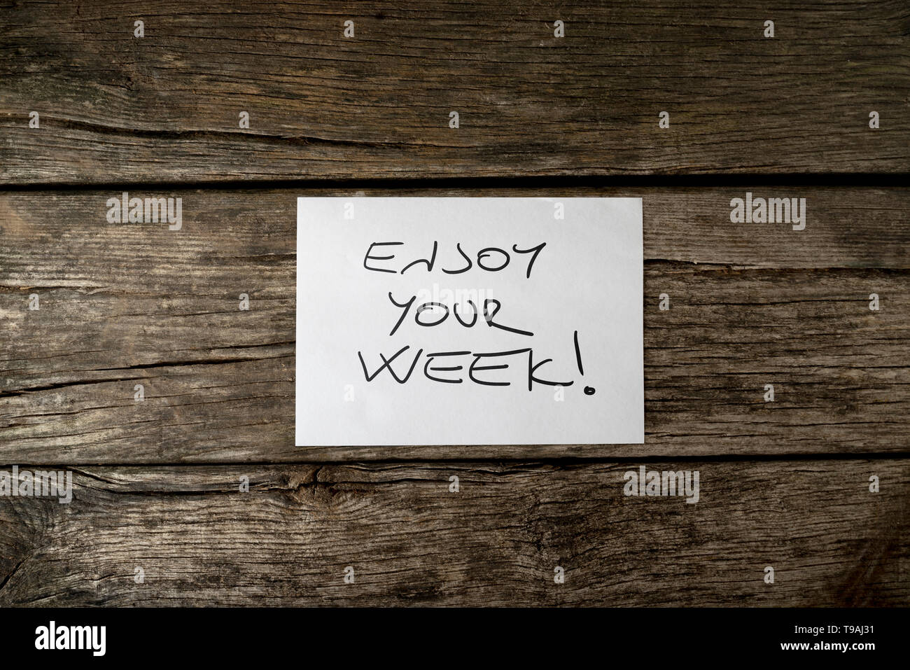Top view Enjoy your week message on a white card lying on textured ...