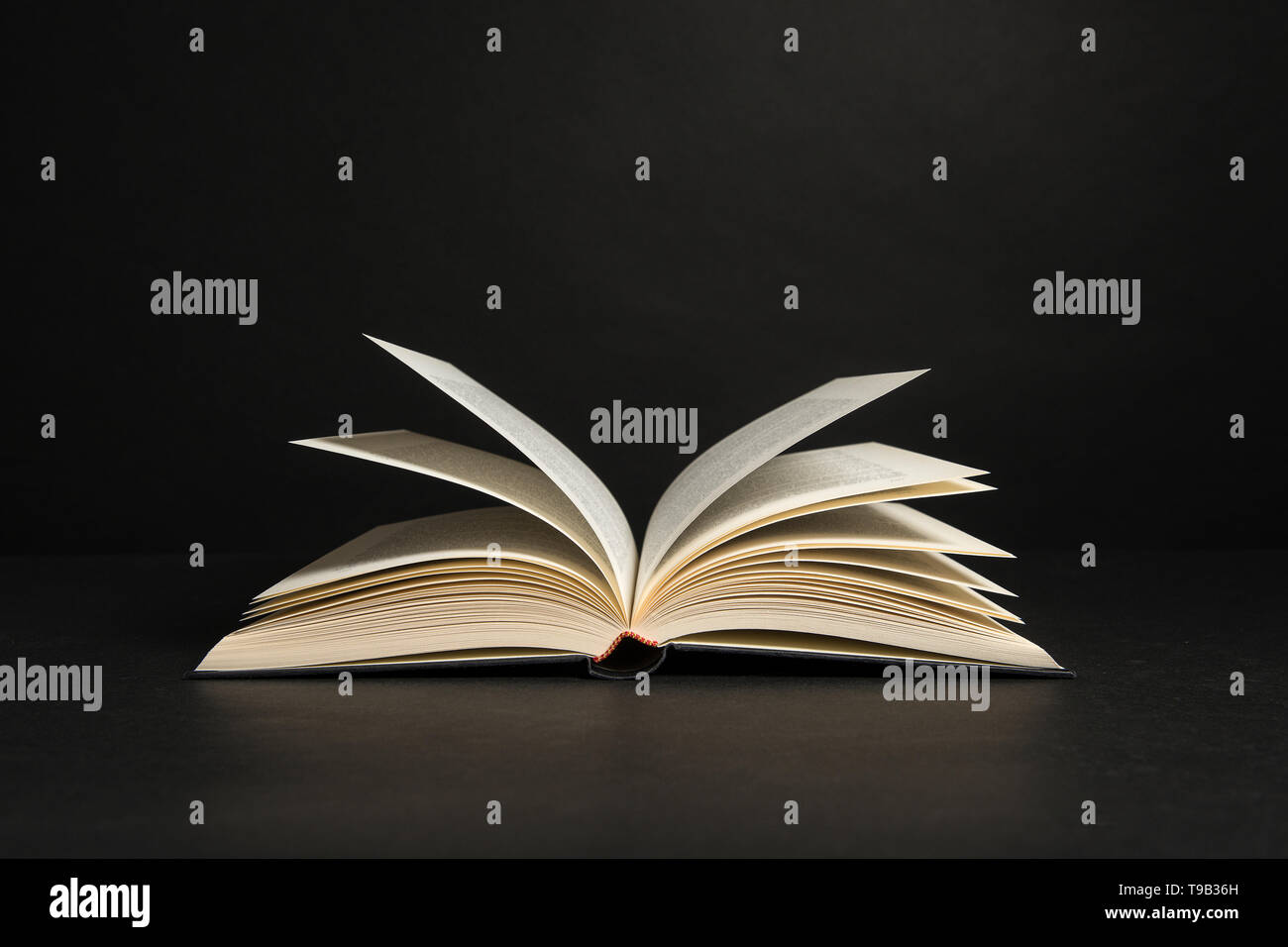 Open book with pages on a black background Stock Photo - Alamy