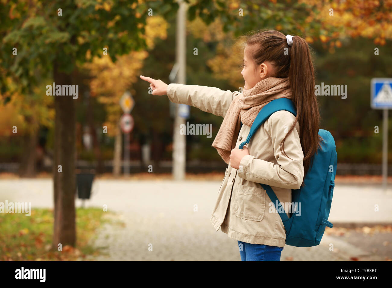 Cute girl with backpack pointing at something outdoors Stock Photo - Alamy