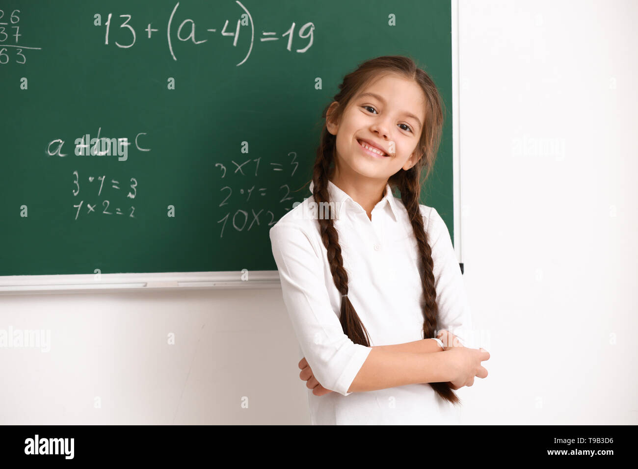 Cute girl standing near chalkboard in classroom Stock Photo - Alamy