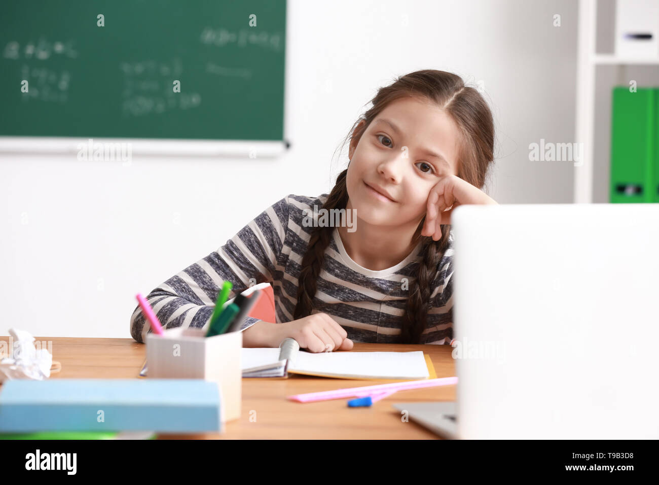 Cute girl doing homework in classroom Stock Photo - Alamy