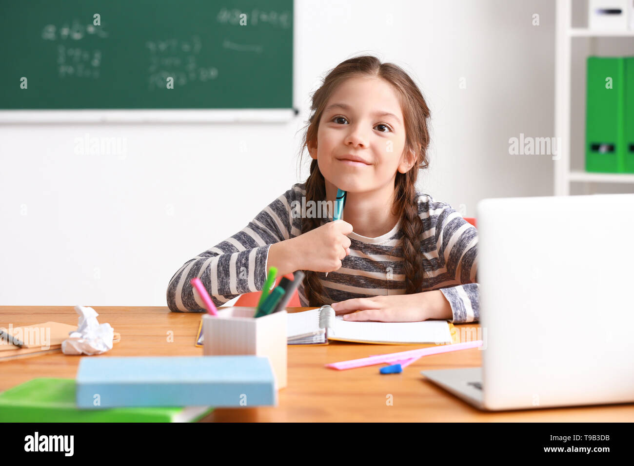 Cute girl doing homework in classroom Stock Photo - Alamy
