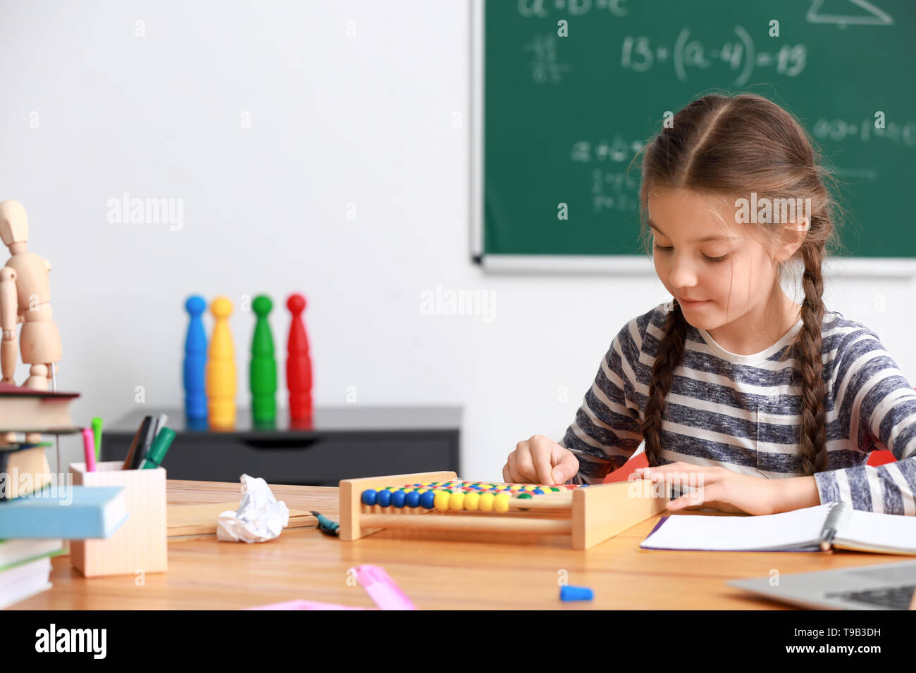 Cute girl doing homework in classroom Stock Photo - Alamy