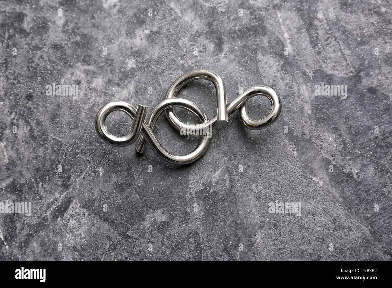Metal brain teaser on grey textured background Stock Photo - Alamy