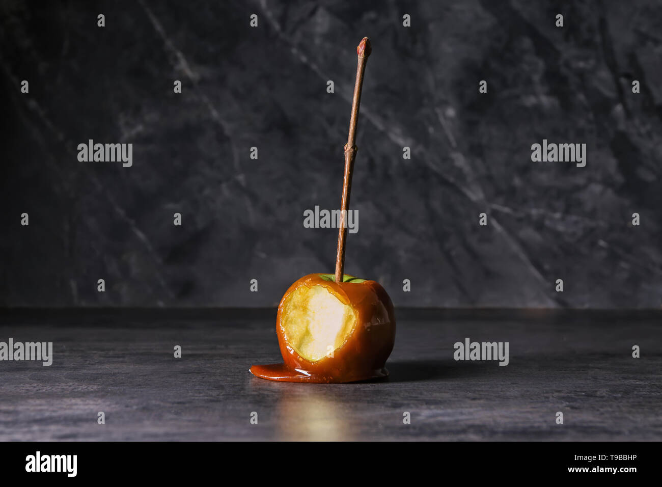 Bitten caramel apple with tree branch on grey table Stock Photo - Alamy