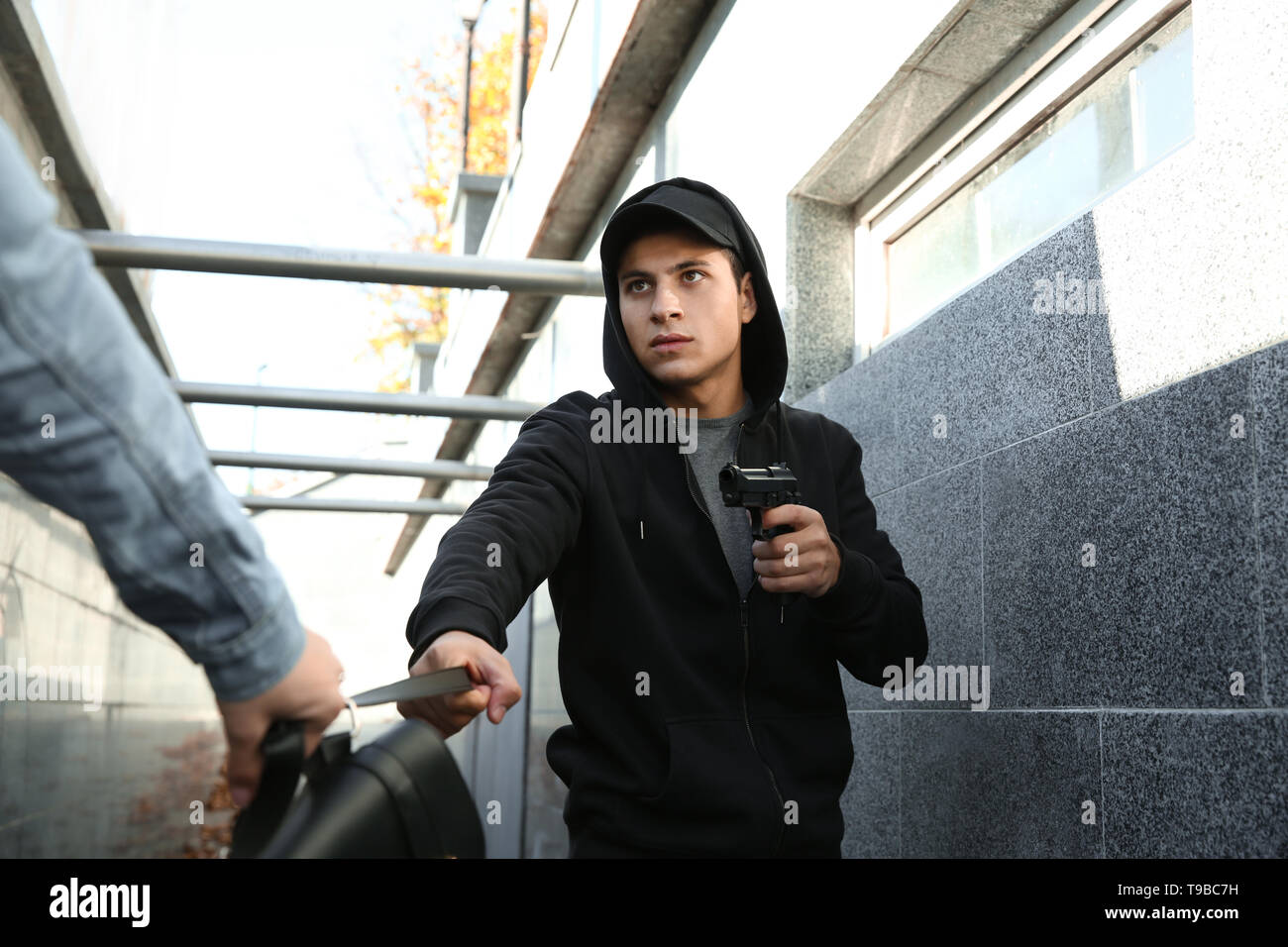 Male thief with gun stealing bag from woman outdoors Stock Photo - Alamy