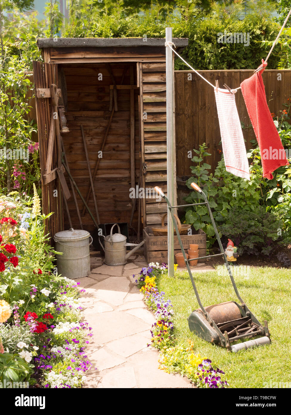 Retro domestic garden with crazy paving path, grass, shed, washing line ...