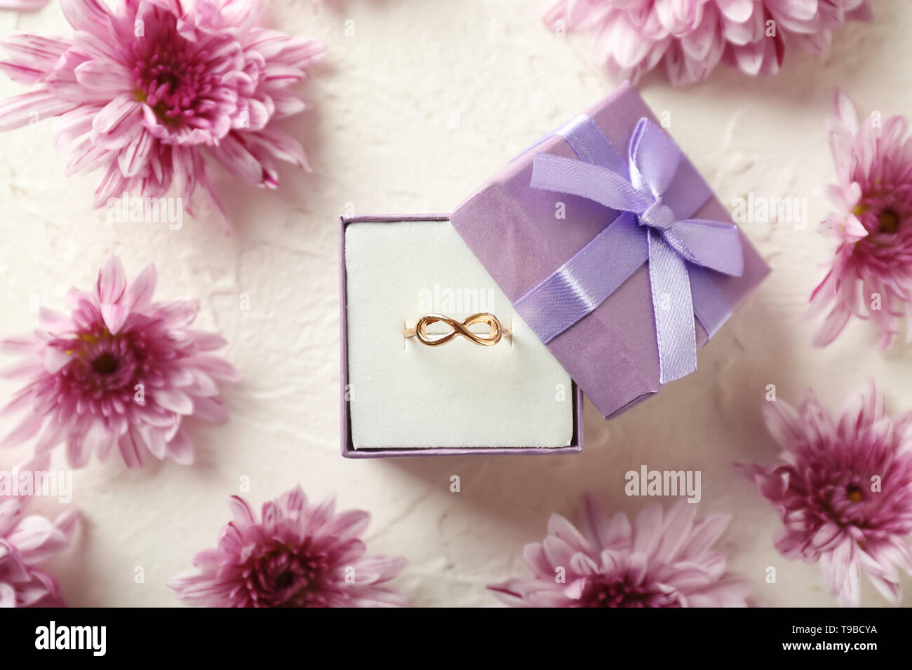 Box with engagement ring and chrysanthemum flowers on white textured ...