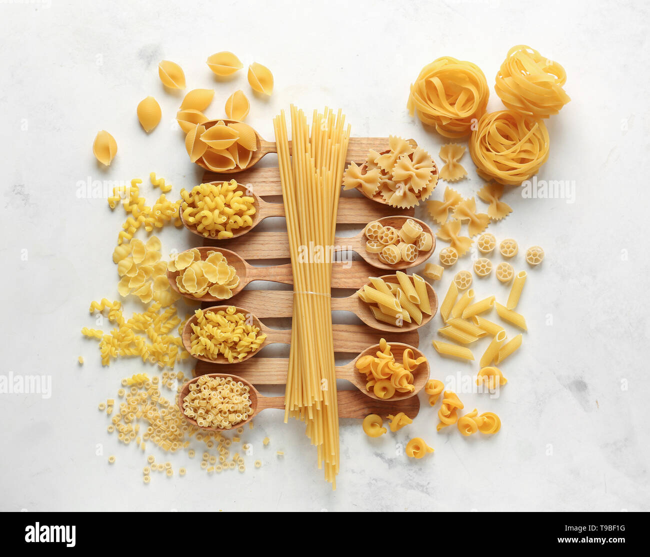 Spoons with different types of raw pasta on white table Stock Photo - Alamy