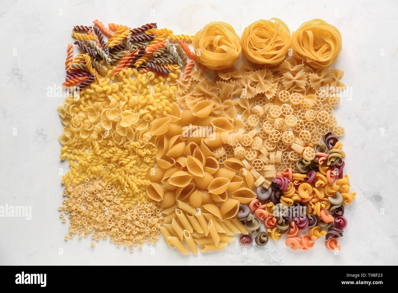 Different types of raw pasta on light background Stock Photo - Alamy