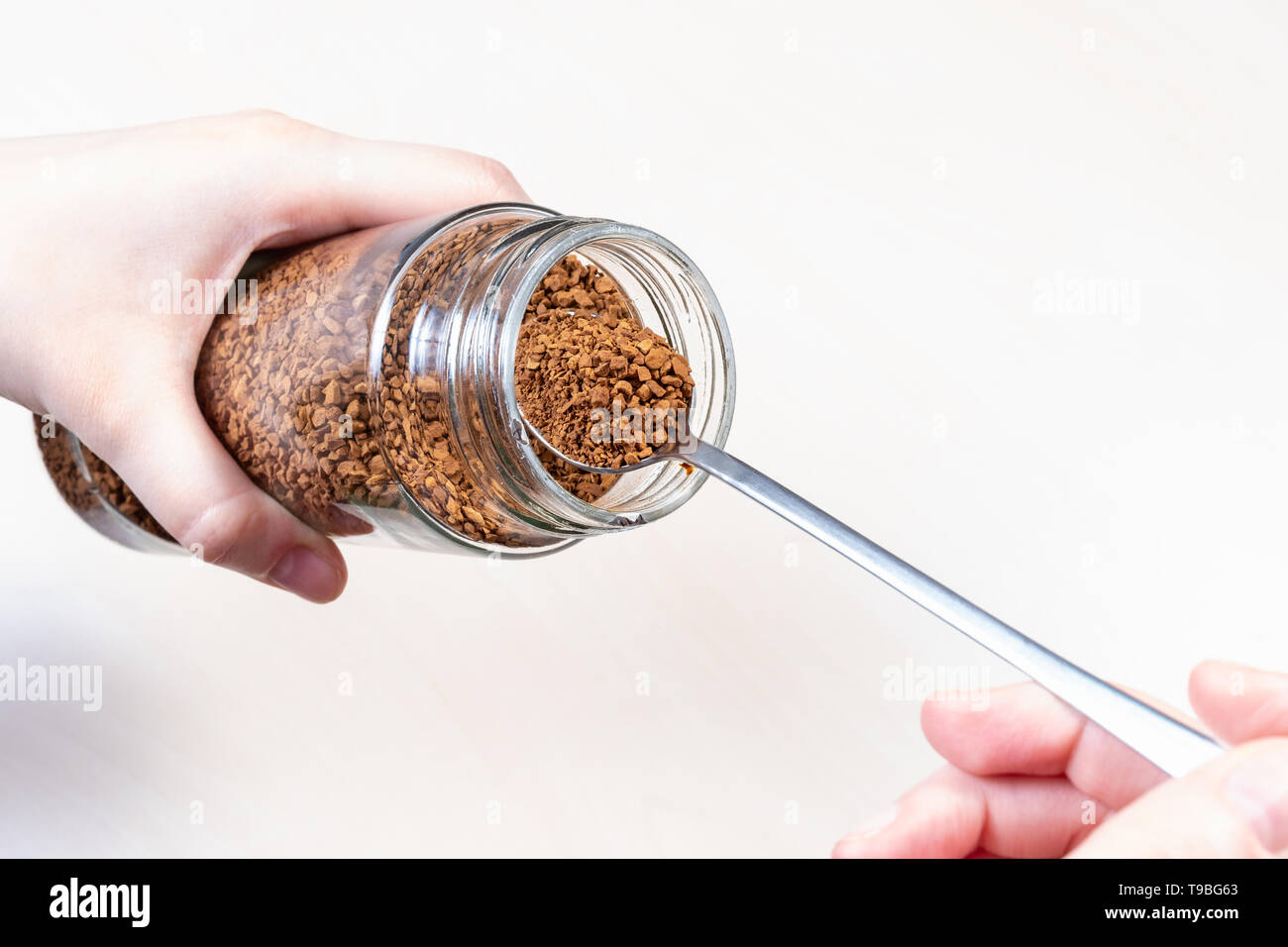 hand spooning up instant coffee from glass jar over table Stock Photo ...