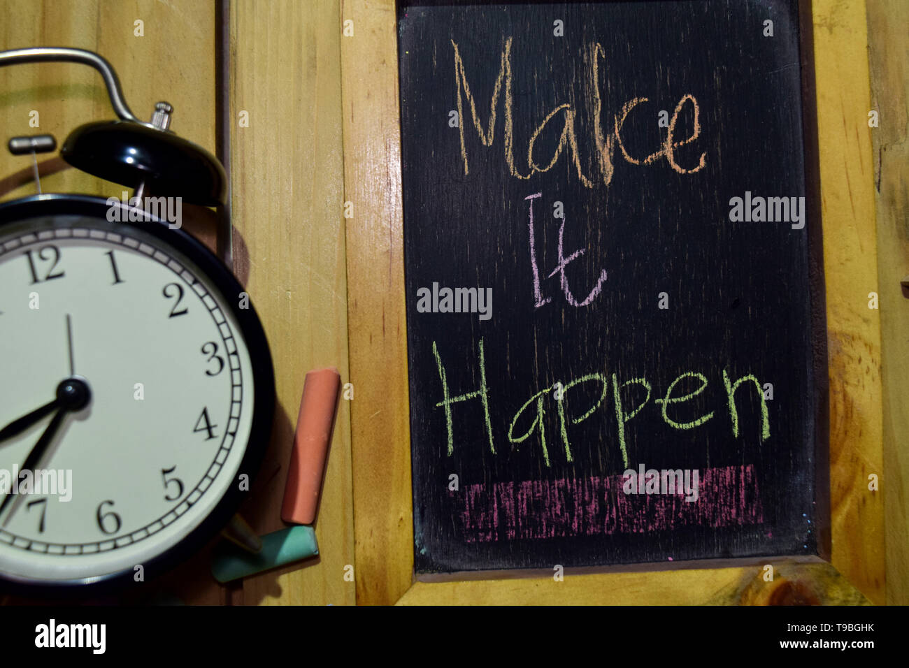 make-it-happen-on-phrase-colorful-handwritten-on-chalkboard-and-alarm