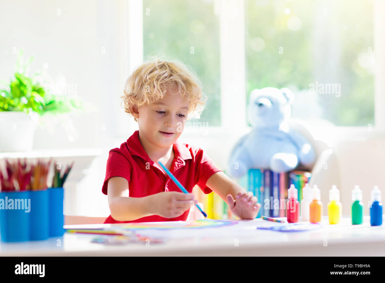 Kids paint. Child painting in white sunny study room. Little boy ...