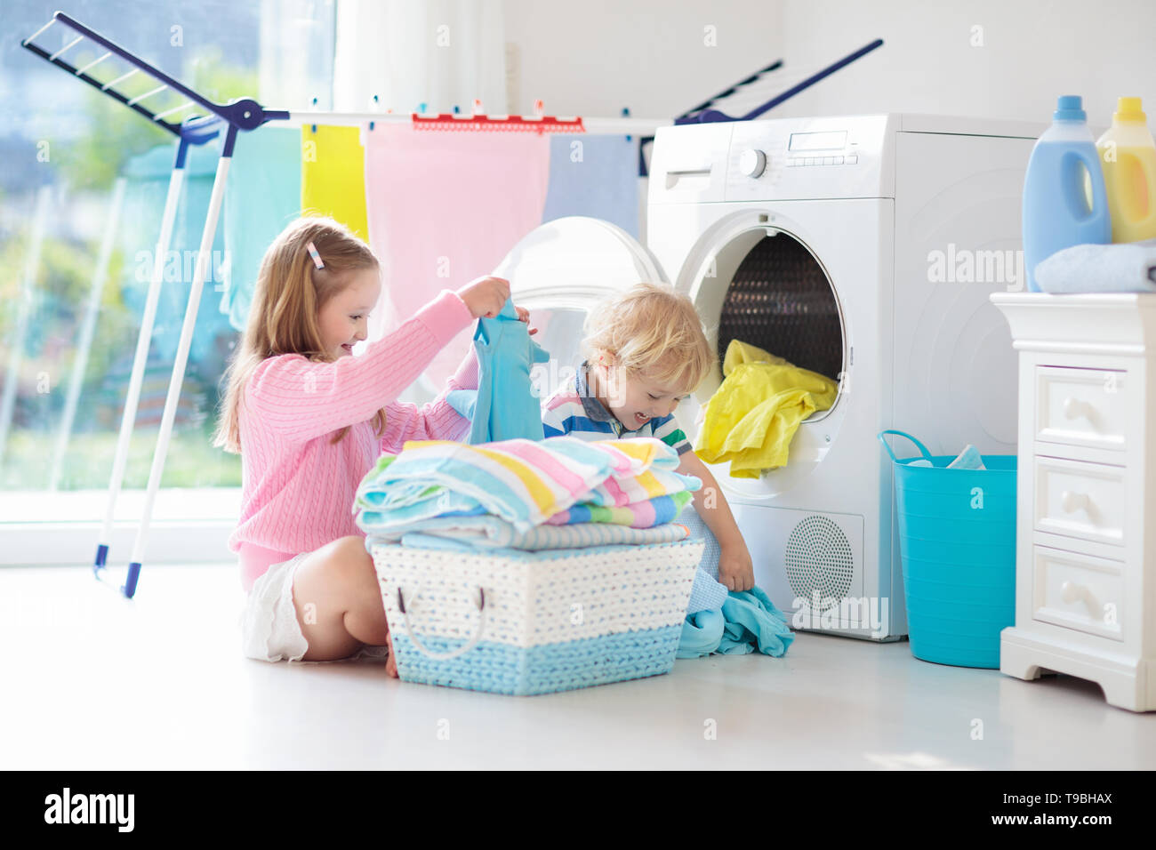 Children in laundry room with washing machine or tumble dryer. Kids ...