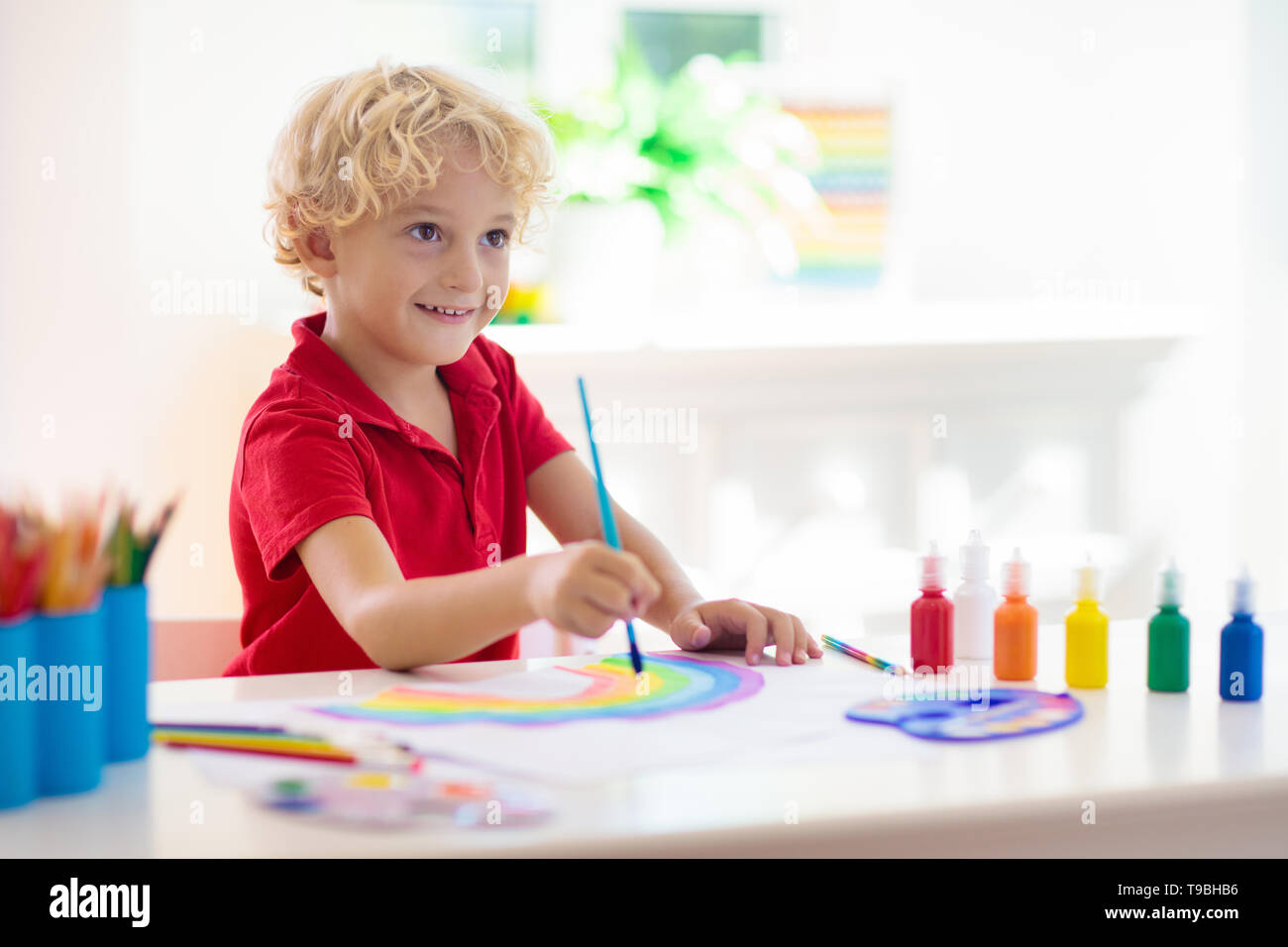 Kids paint. Child painting in white sunny study room. Little boy ...