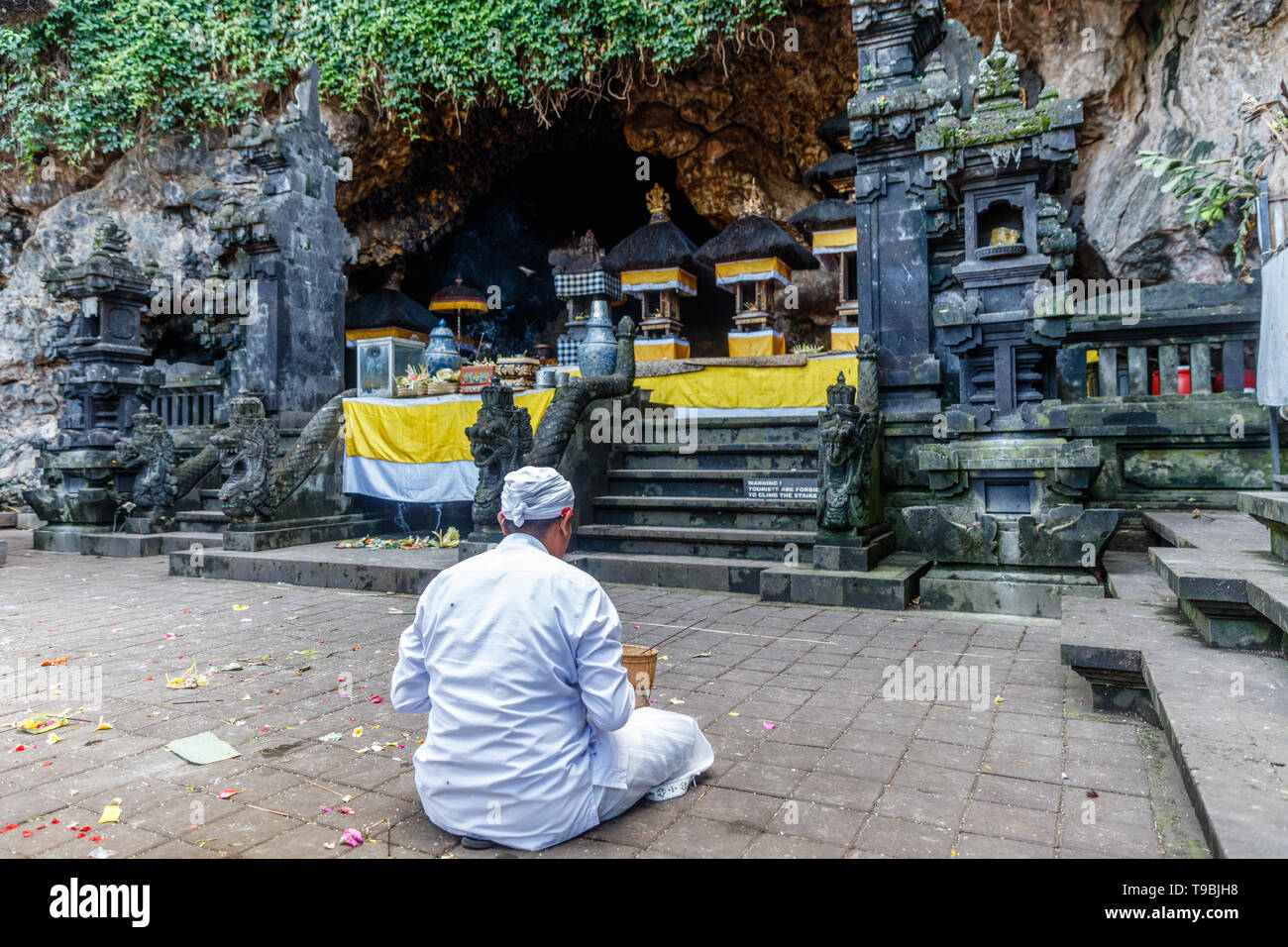 Hindu priest praying at Pura Goa Lawah ("Bat Cave Temple"), Balinese ...