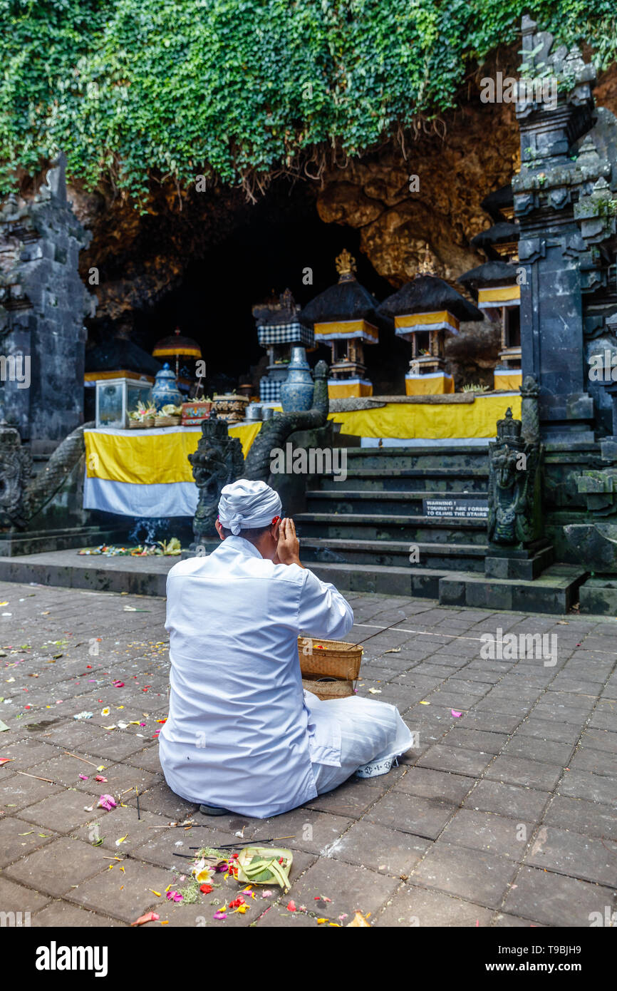 Hindu priest praying at Pura Goa Lawah ("Bat Cave Temple"), Balinese ...