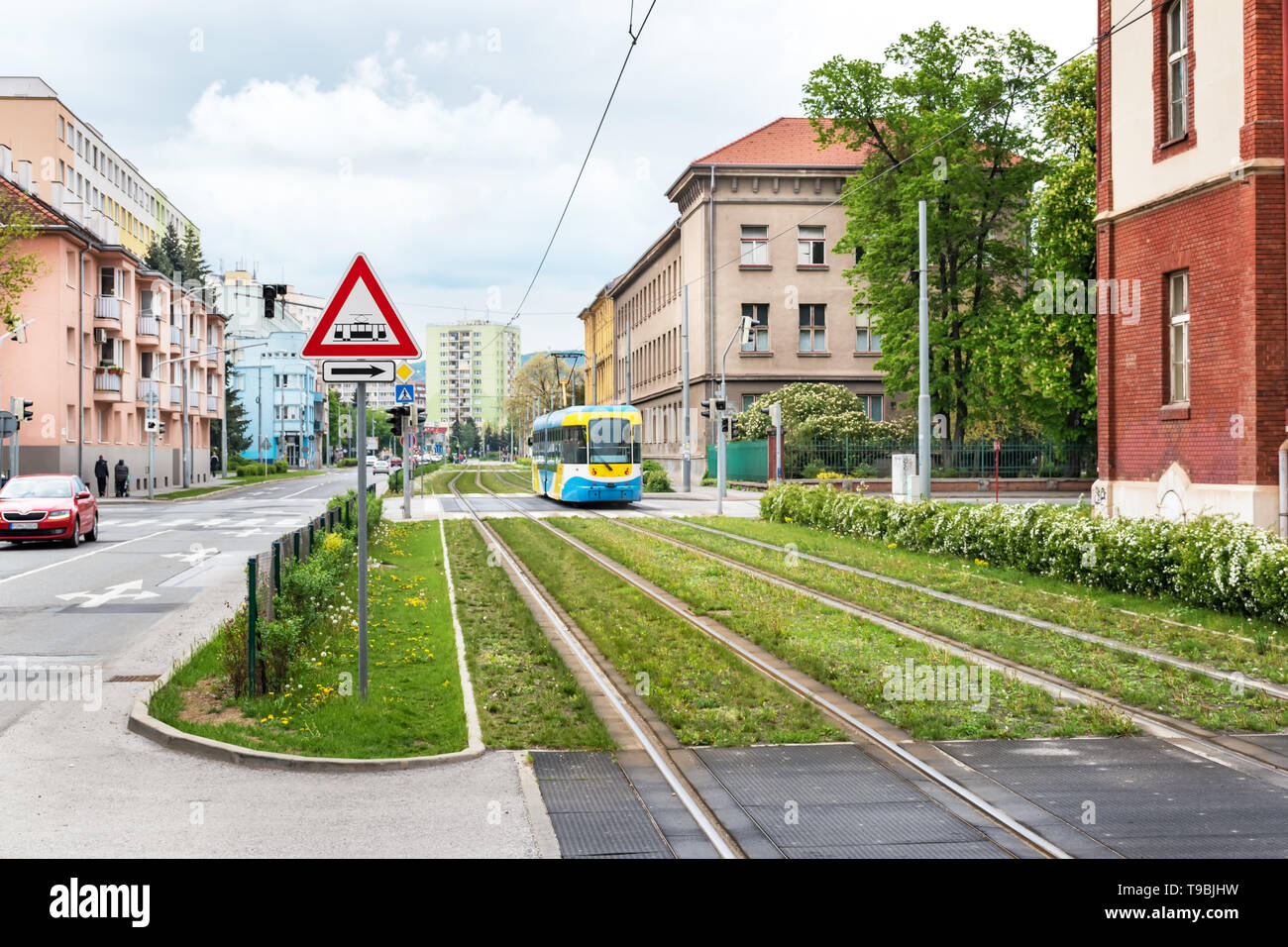 Colourful tram runs on tramway track over green grass area in Kosice ...
