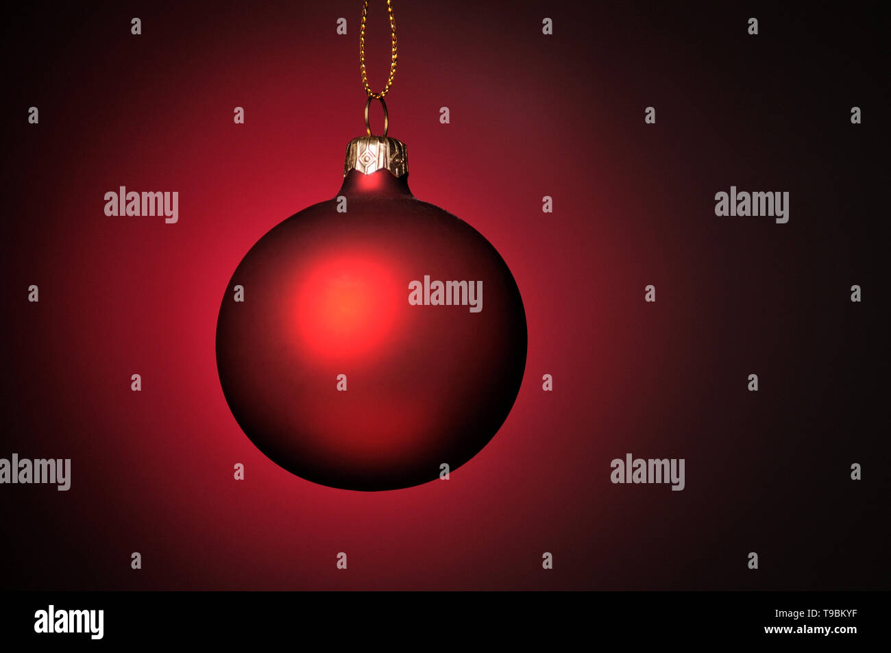 Red Christmas bauble hanging on a gold string Stock Photo - Alamy