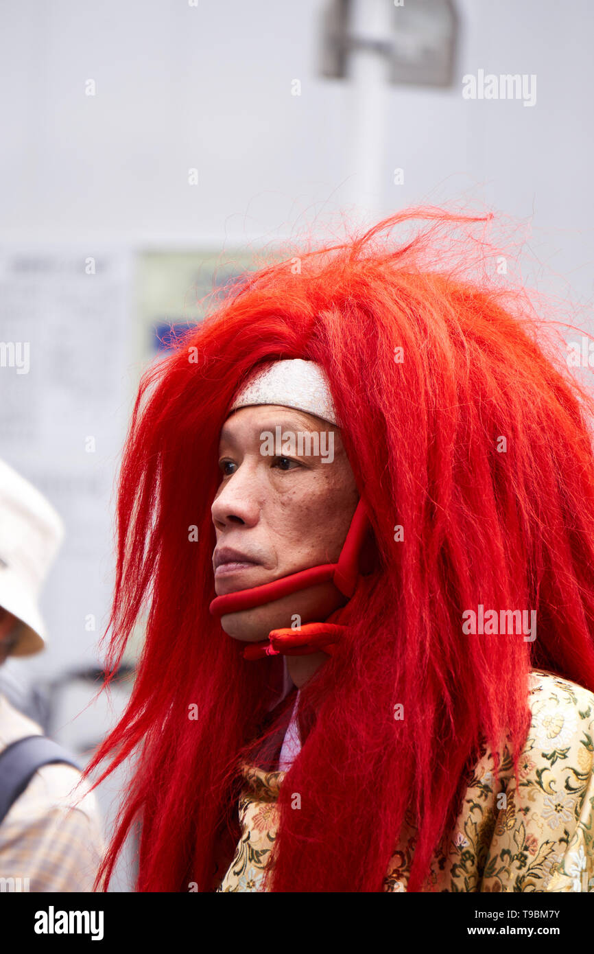 Japanese man in vibrant red wig and chin straps dressed as oni (ogre ...