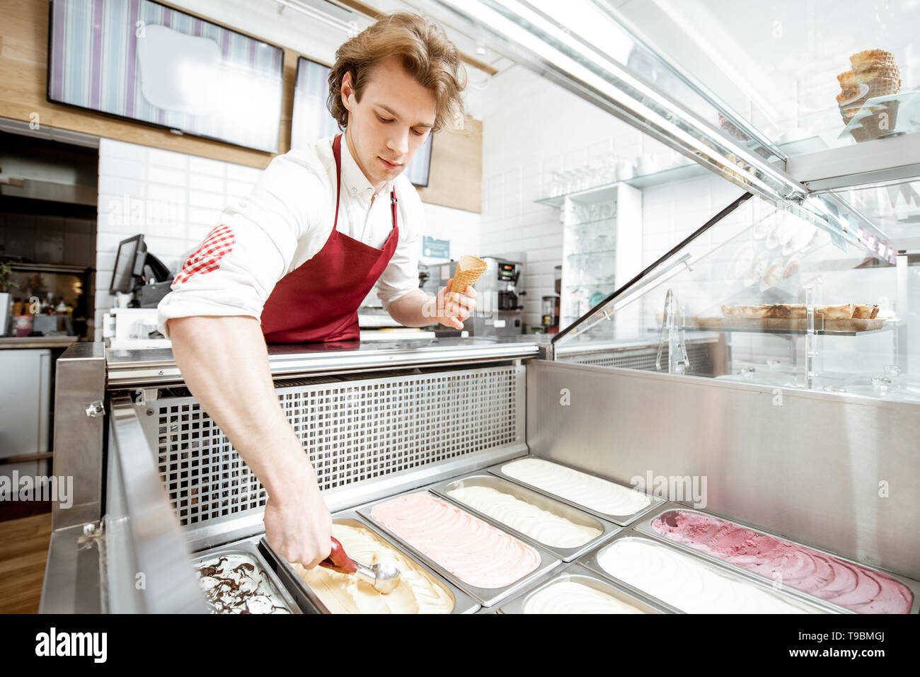 Salesman taking ice cream from the trays on the showcase refrigerator ...