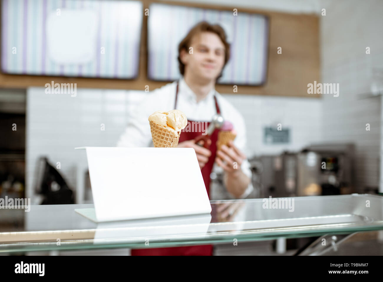 Ice cream on the counter with salesman working on the background in the ...