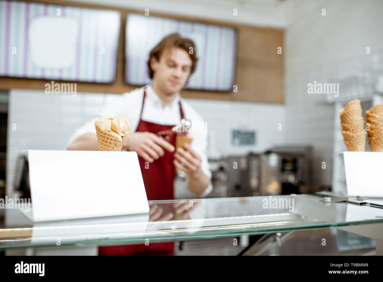 Ice cream on the counter with salesman working on the background in the ...