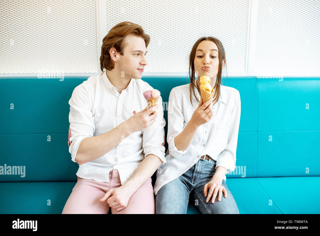 Young couple having fun, enjoying ice cream while sitting together on ...