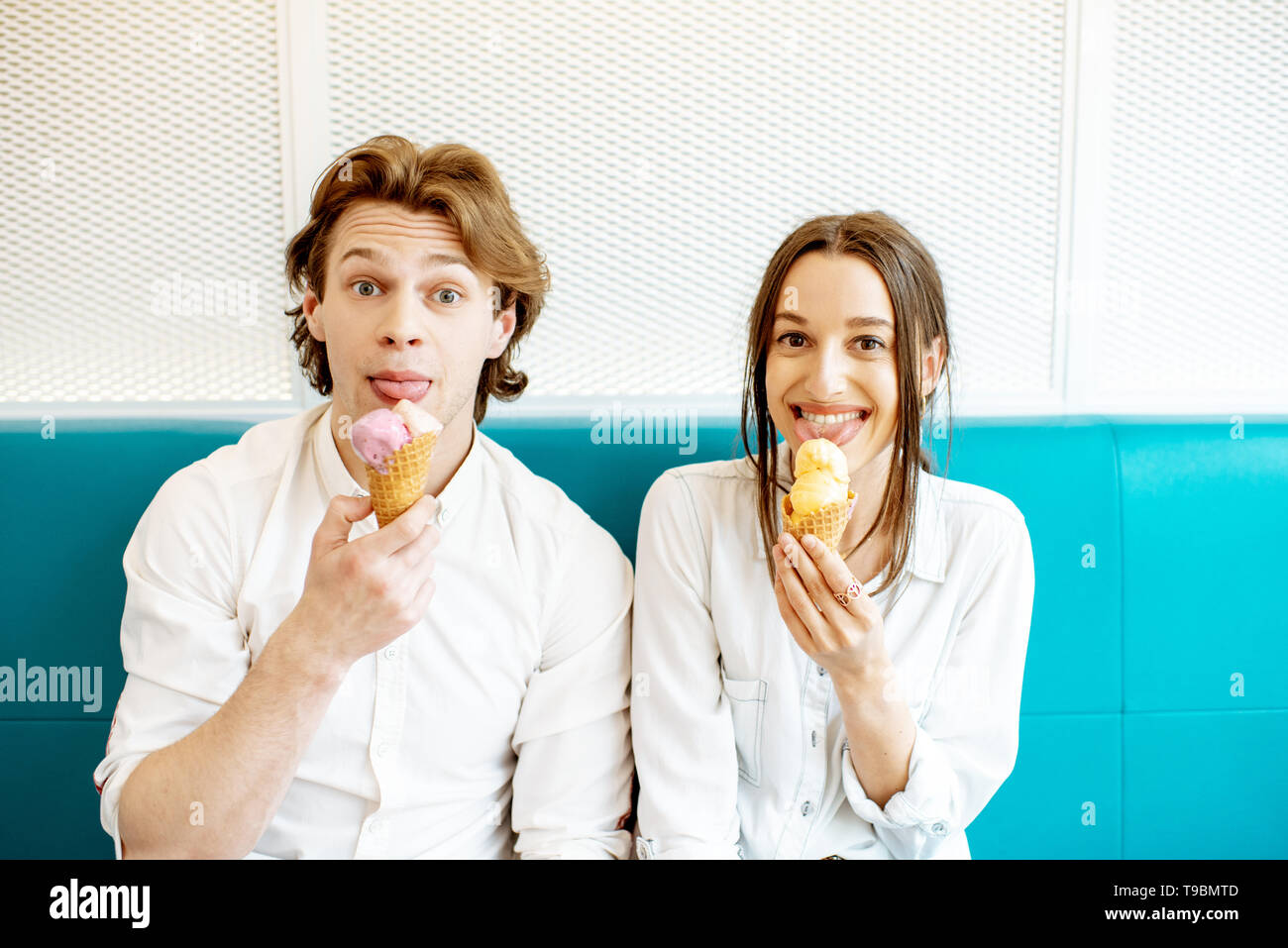 Young couple having fun, enjoying ice cream while sitting together on ...