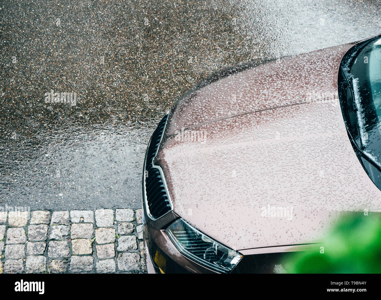 View from above over new car covered with tiny hail during heavy rain ...