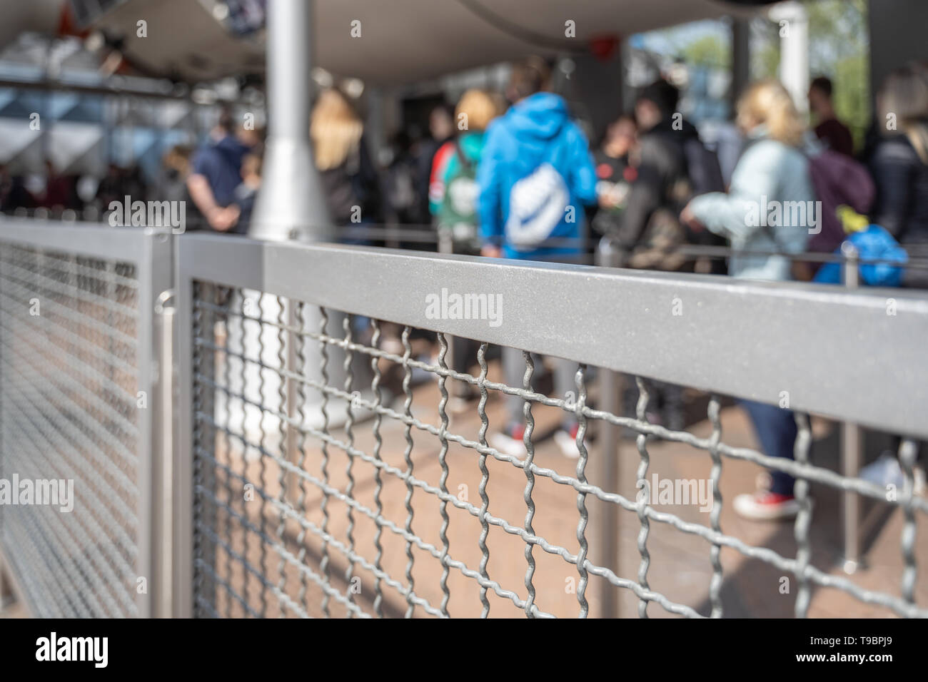 Queue in a park with a security fence. (Focus on the fence with ...