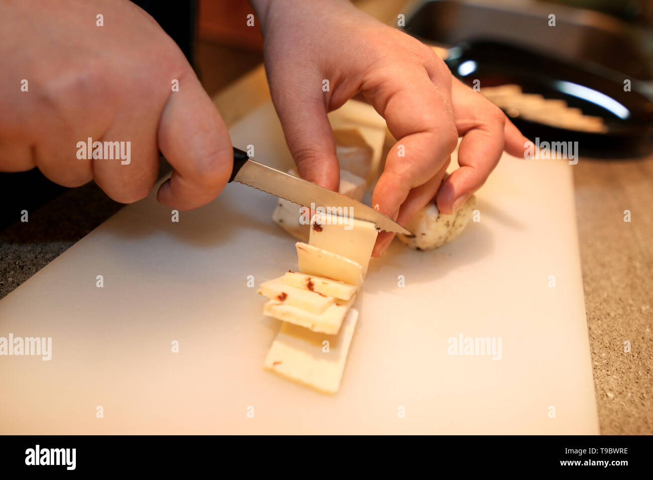 Woman hands cutting piece of cheese, she prepare food at kitchen. Chef ...
