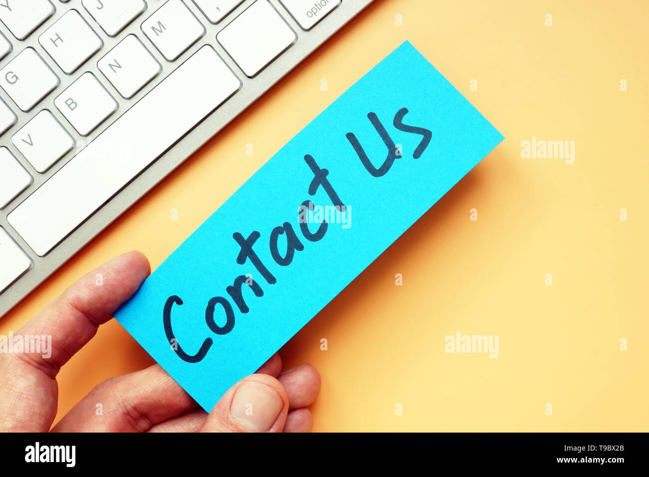 Hand holds sign Contact us and keyboard Stock Photo - Alamy