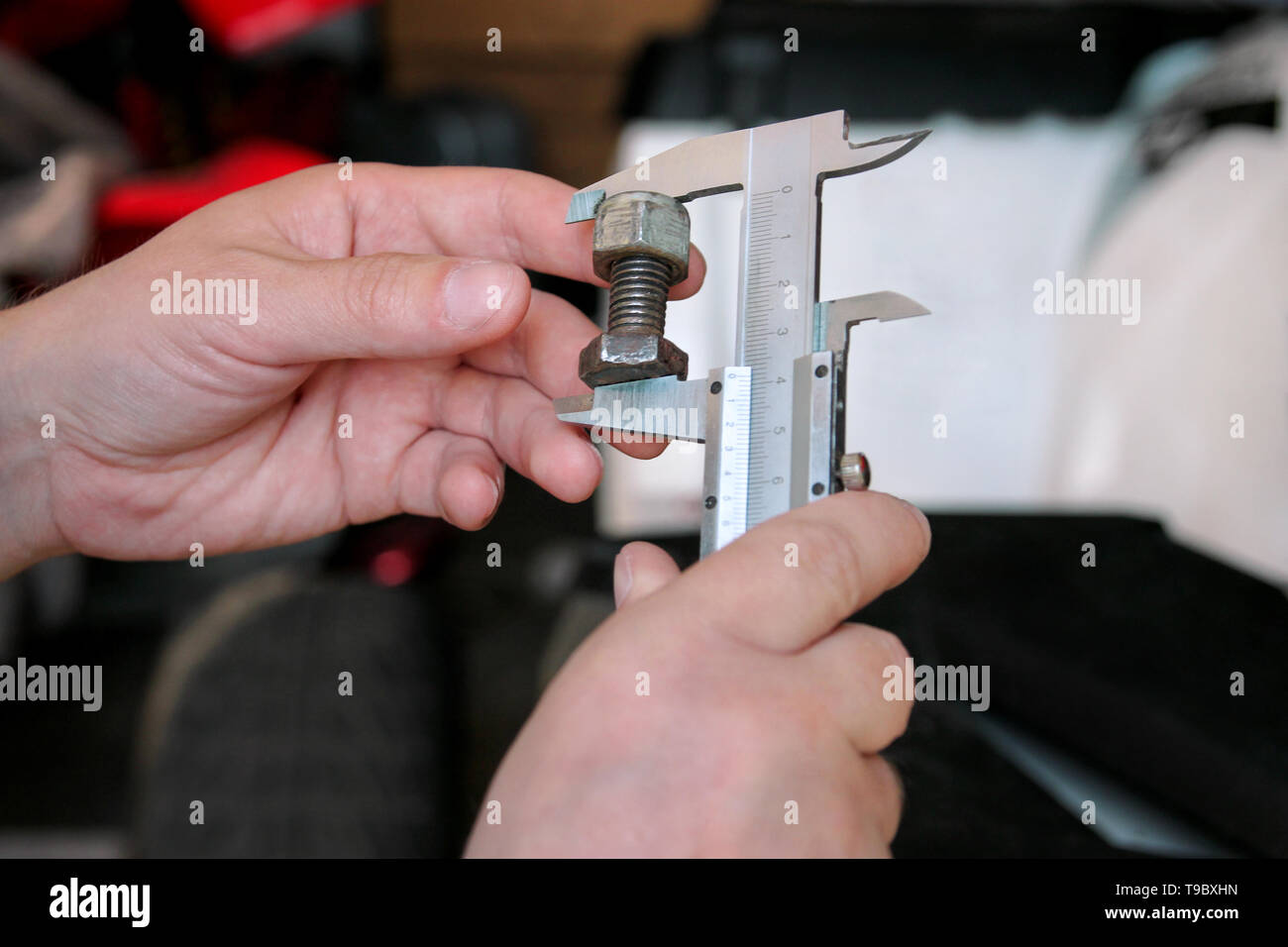 Worker with tools in hands. Mechanic is checking and measuring screw ...