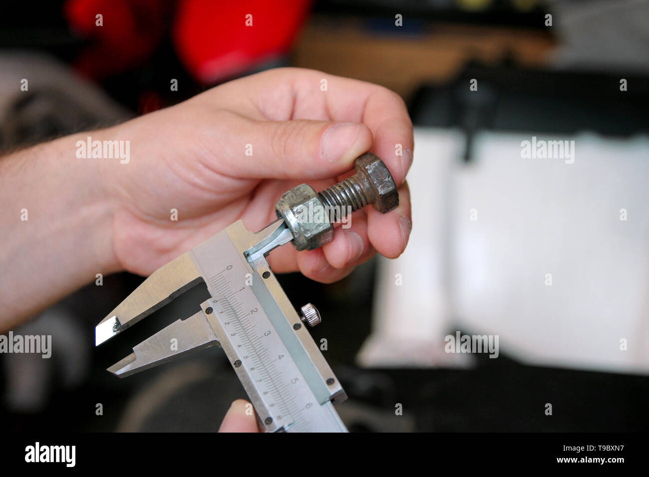 Worker with tools in hands. Mechanic is checking and measuring screw ...